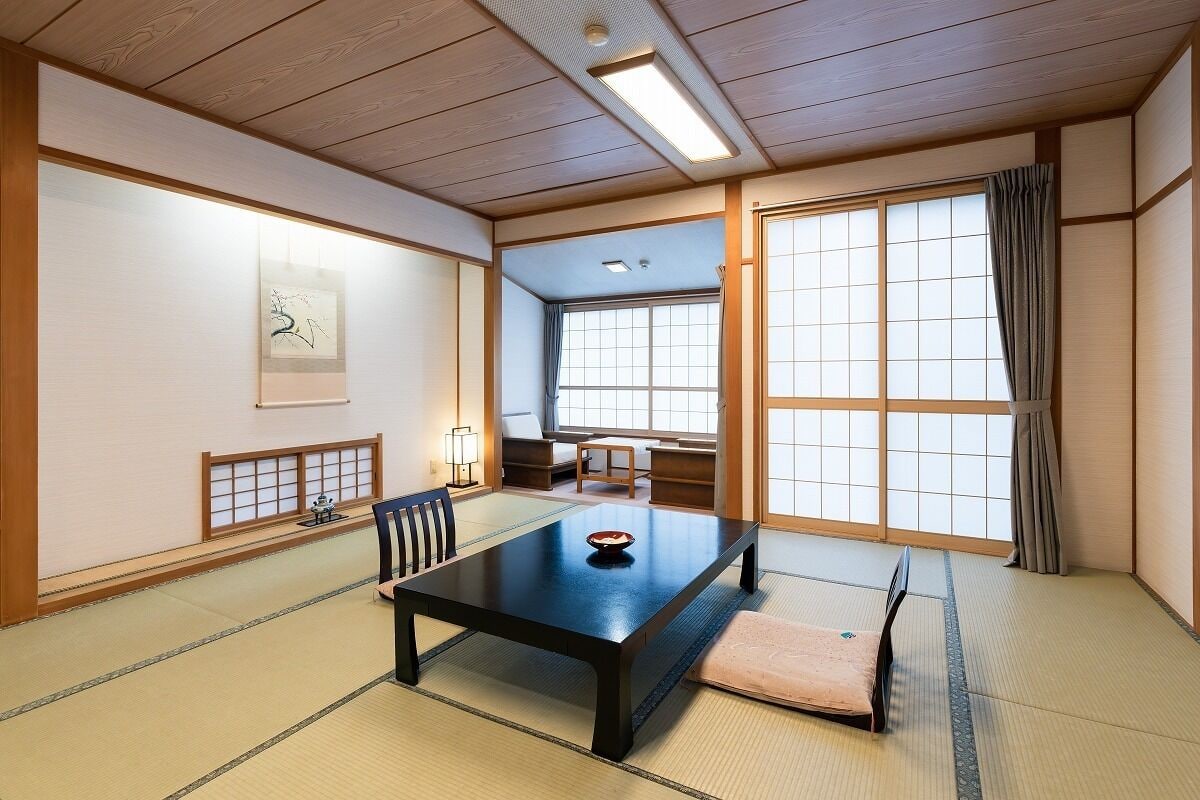 Um quarto japonês tradicional com tatames, uma mesa baixa e portas deslizantes.