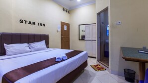 Quarto de hotel com cama, escrivaninha e espelho. O quarto tem uma porta e uma parede com a placa "STAR INN".