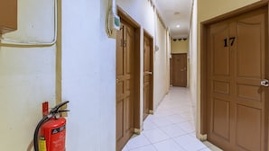 Um corredor com portas numeradas 15 e 17, um extintor fixado na parede e chão de azulejos.