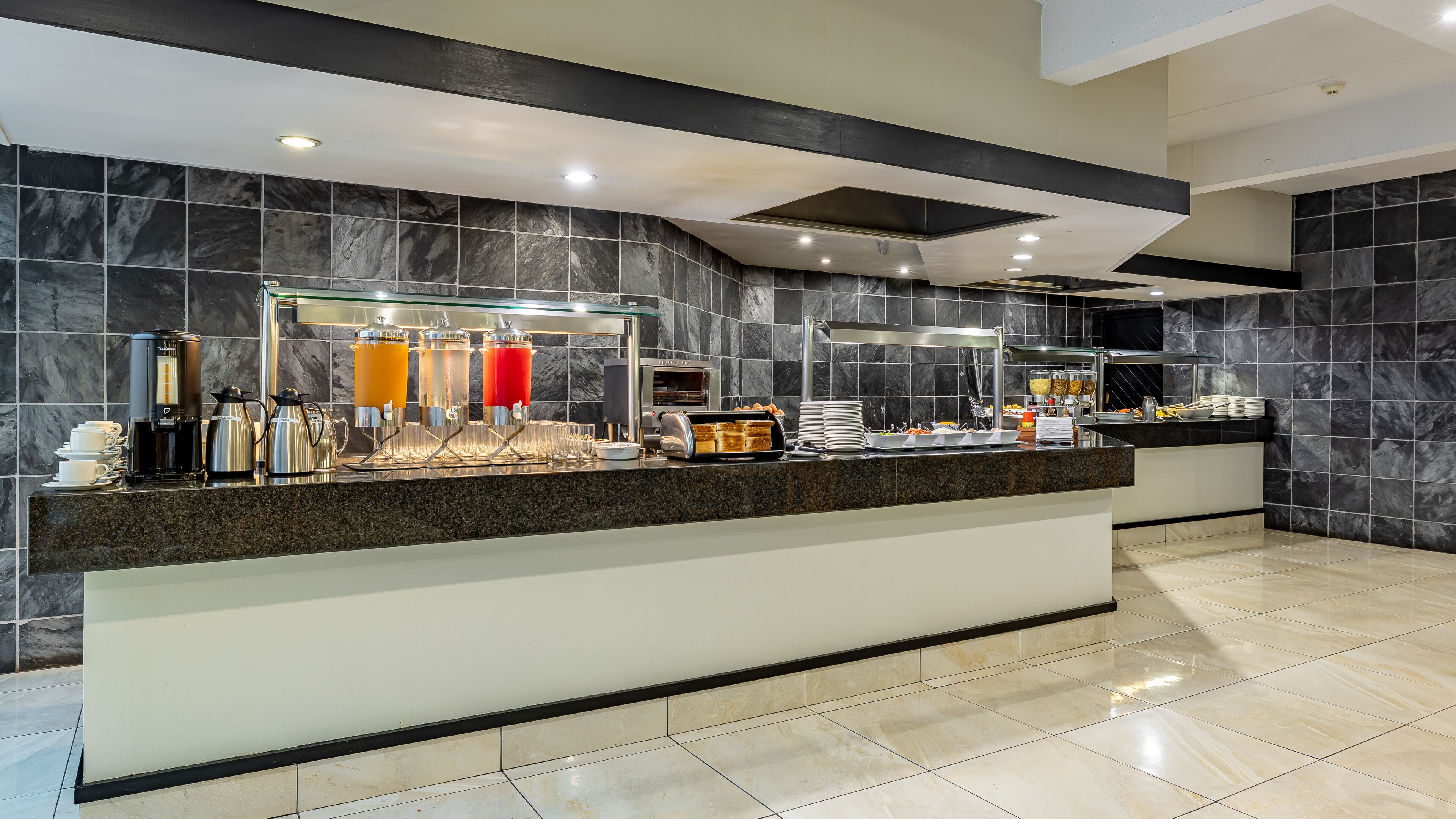 Uma moderna ilha de café da manhã, com estação de café, dispensadores de suco e torradeira.