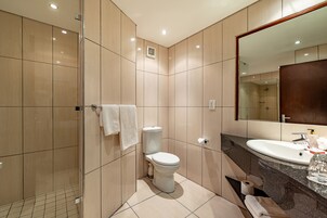 Uma casa de banho moderna com sanita, lavatório e chuveiro.