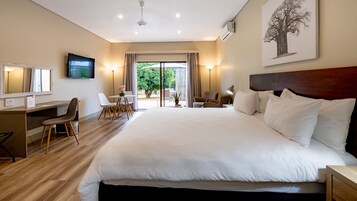 Quarto de hotel com uma cama grande, uma escrivaninha com cadeira, televisão e vista para o exterior.
