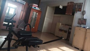 Quarto com esteira, armários de madeira, uma pequena cesta de basquete e televisão na parede.