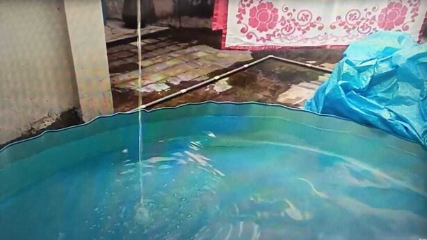 Uma piscina pequena e retangular com uma lona azul de um lado.