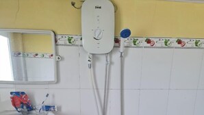 Casa de banho com lavatório branco, um balde vermelho, sanita e cabine de duche.