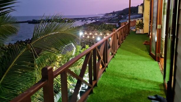 Varanda com guarda-mão de madeira com vista para uma praia e oceano.