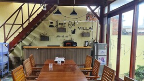 Uma mesa de jantar de madeira com cadeiras, uma escada e uma parede com a placa que diz "House Cat Villa".