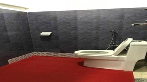 Casa de banho com sanita branca, lavatório branco e chuveiro.