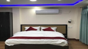 Quarto de hotel com cama, guarda-roupa, ar condicionado e luminária na parede.