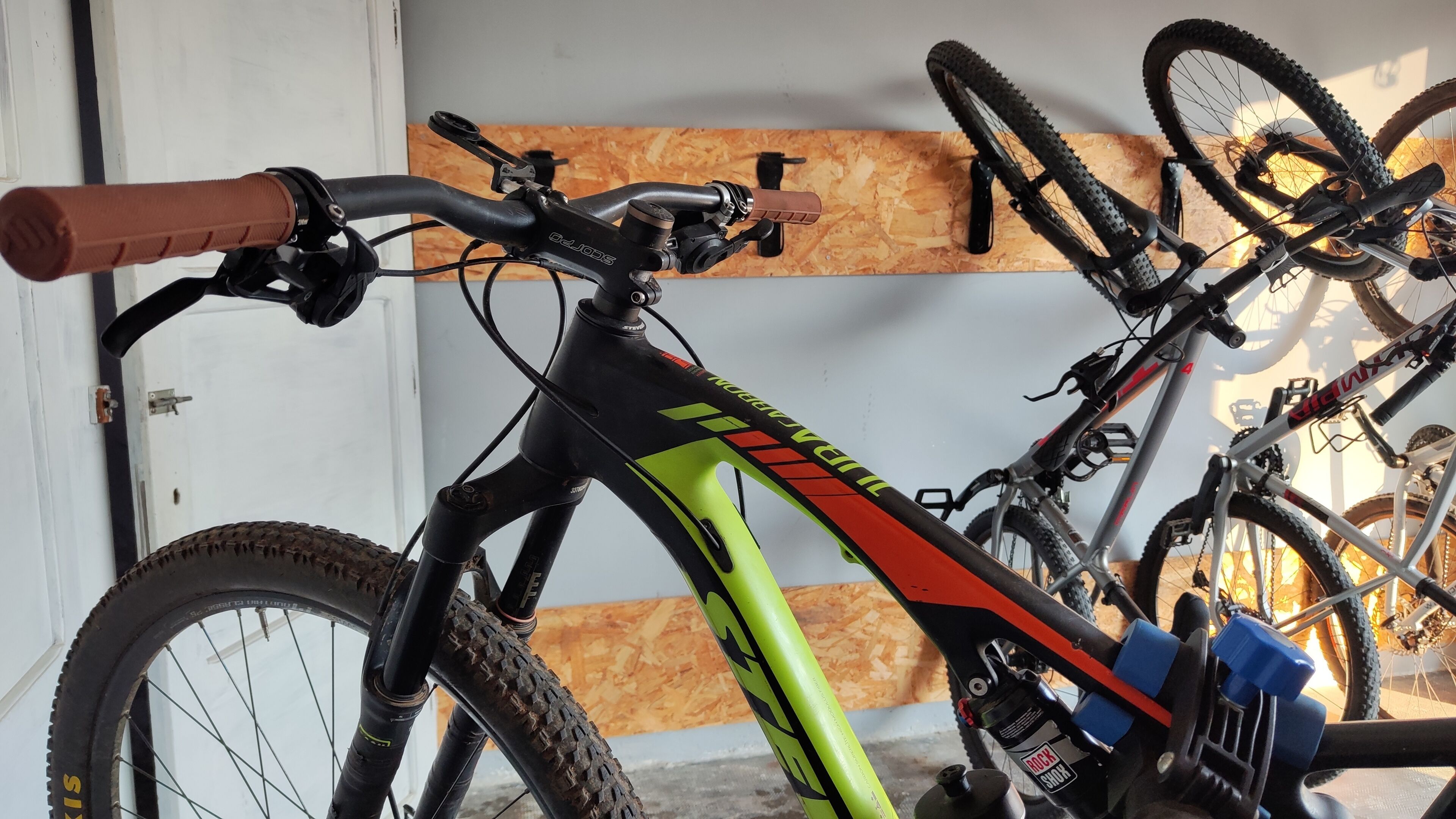 Uma bicicleta com quadro preto e neon verde, guidão marrom e bagageiro traseiro.
