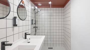 Uma casa de banho moderna com paredes revestidas de azulejos brancos, uma sanita branca com torneiras pretas e uma área de duche.