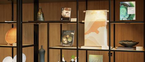 Exposição de objetos decorativos, incluindo cerâmicas, um vaso e uma obra de arte emoldurada, em prateleiras.