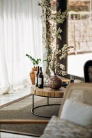 Uma área de estar acolhedora com uma mesa de madeira redonda, um vaso com flores e duas garrafas de vinho.