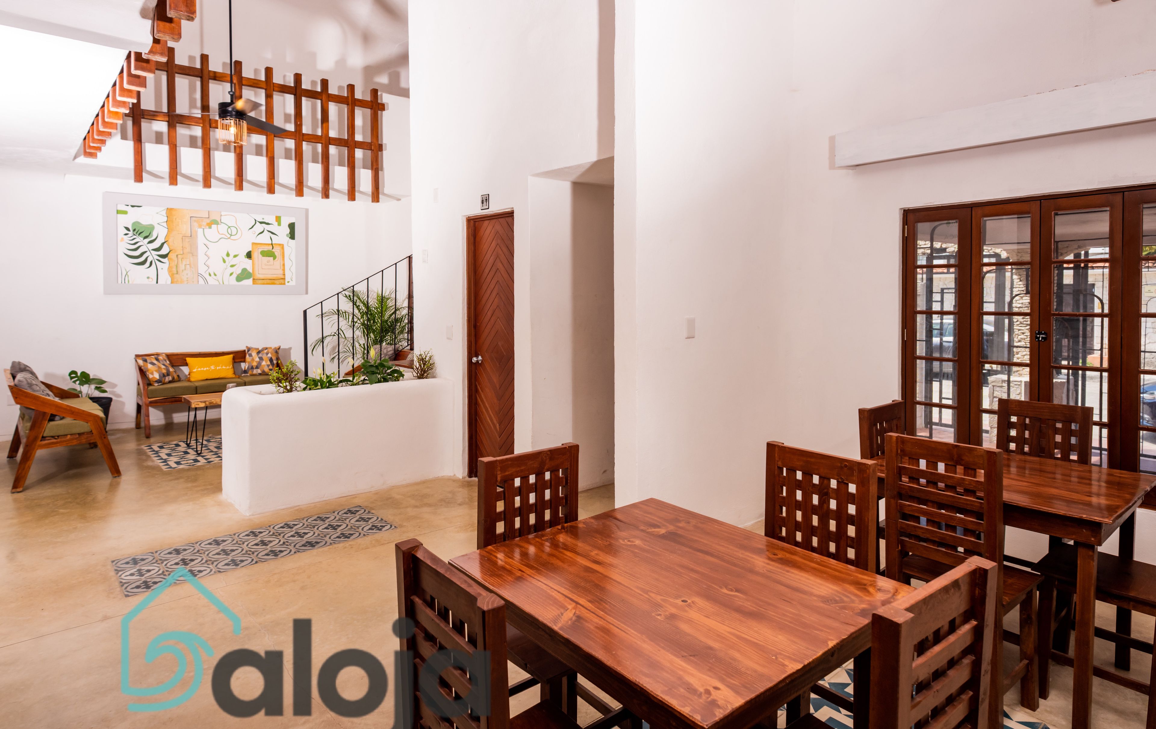 Uma sala de estar ampla com uma mesa de jantar de madeira e cadeiras, uma escada e vista para o exterior.