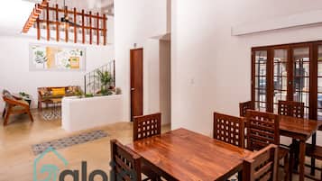 Uma sala de estar ampla com uma mesa de jantar de madeira e cadeiras, uma escada e vista para o exterior.