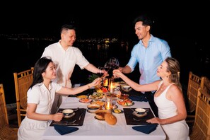 Um grupo de pessoas brindando à mesa de jantar com vista para a cidade à noite.