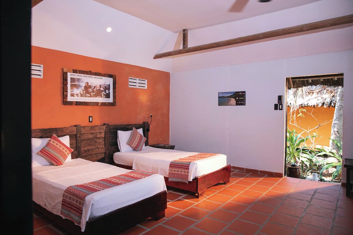 Quarto com duas camas, cabeceira de madeira, quadro na parede e piso em azulejos.