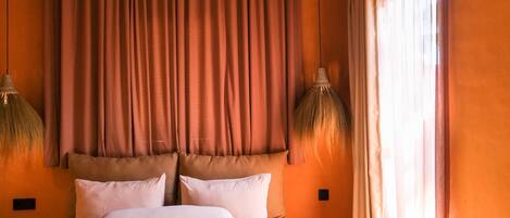 Quarto com uma cama grande, cortinas e duas luminárias na parede.