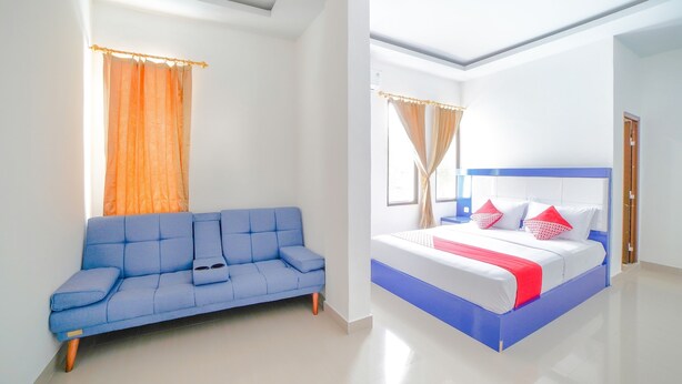 Quarto de hotel moderno com sofá azul, cama com cabeceira azul e design claro e impecável.