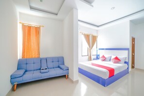 Quarto de hotel moderno com sofá azul, cama com cabeceira azul e design claro e impecável.
