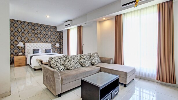 Quarto de hotel moderno com cama, sofá e mesa de centro.