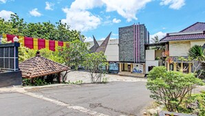 Um pátio com uma estrutura de telhado de cerâmica, um edifício com fachada listrada verticalmente e uma casa tradicional com telhado de cerâmica.