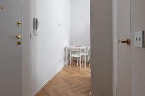 Um corredor com porta branca, telefone e uma pequena mesa com cadeiras.