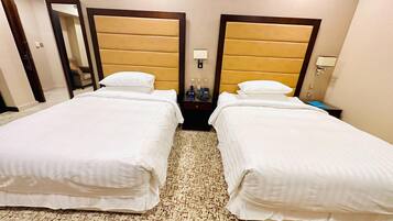 Quarto de hotel com duas camas, uma mesa de cabeceira com telefone e um espelho.