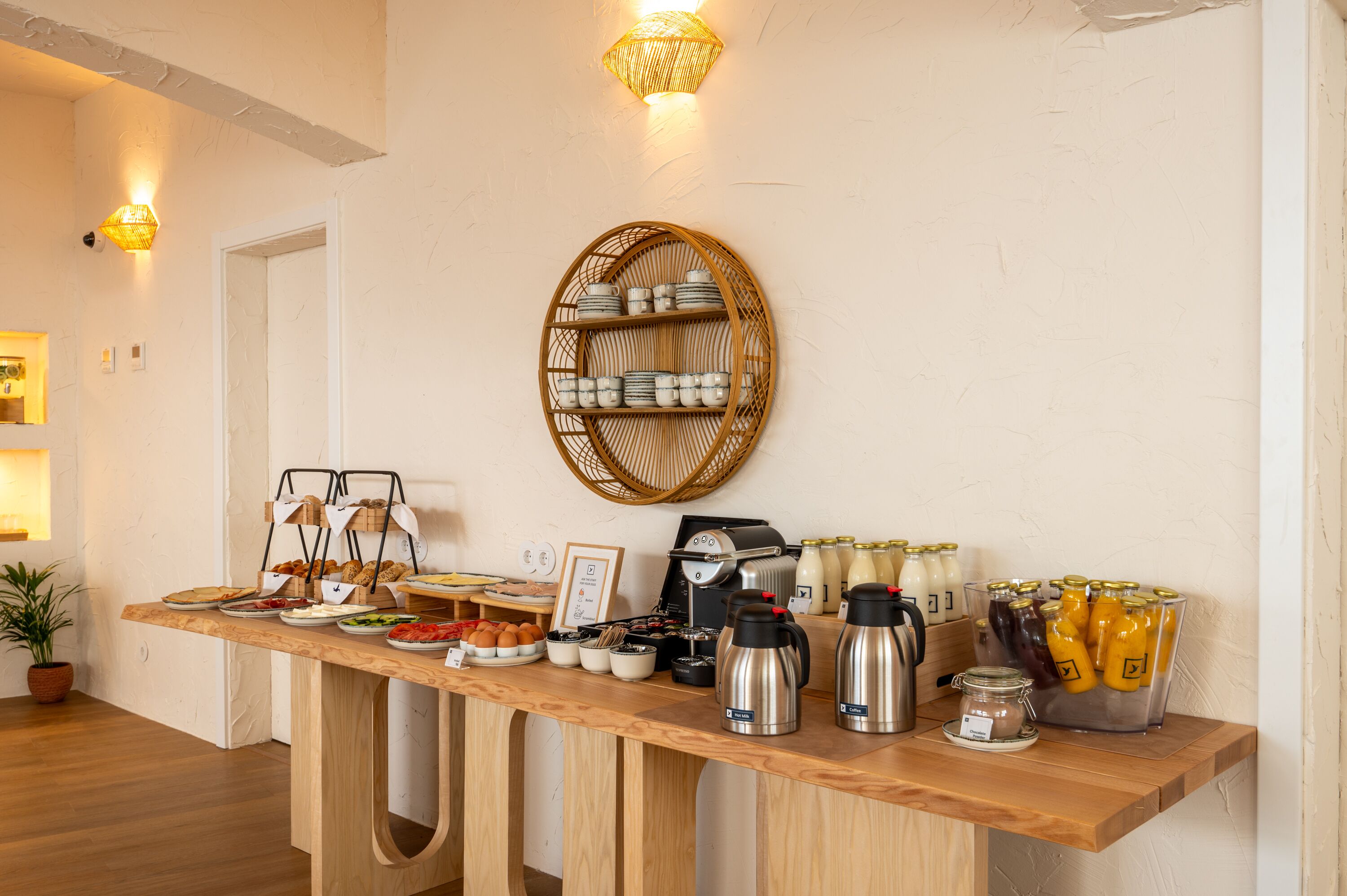Um balcão de café da manhã com diversos alimentos, máquinas de café e acompanhamentos.