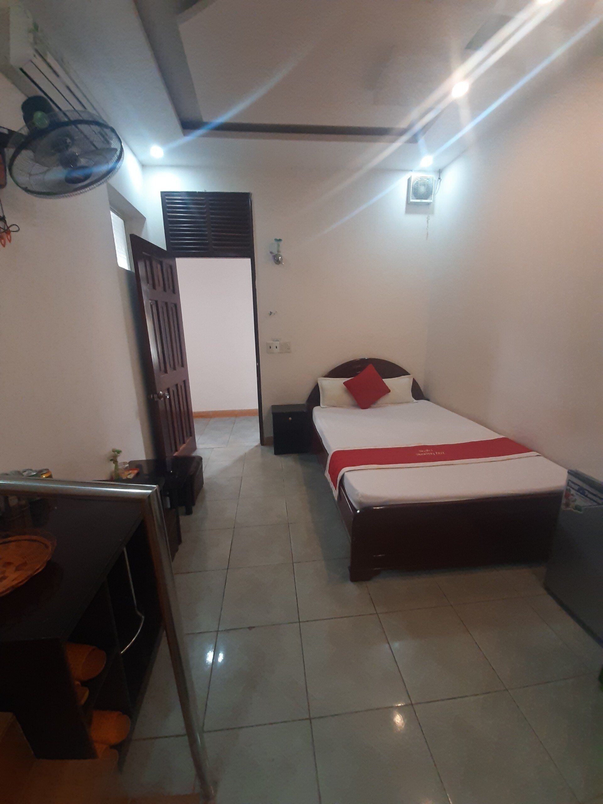 Um quarto com uma cama, mesa de cabeceira e uma pequena escrivaninha com cadeira.
