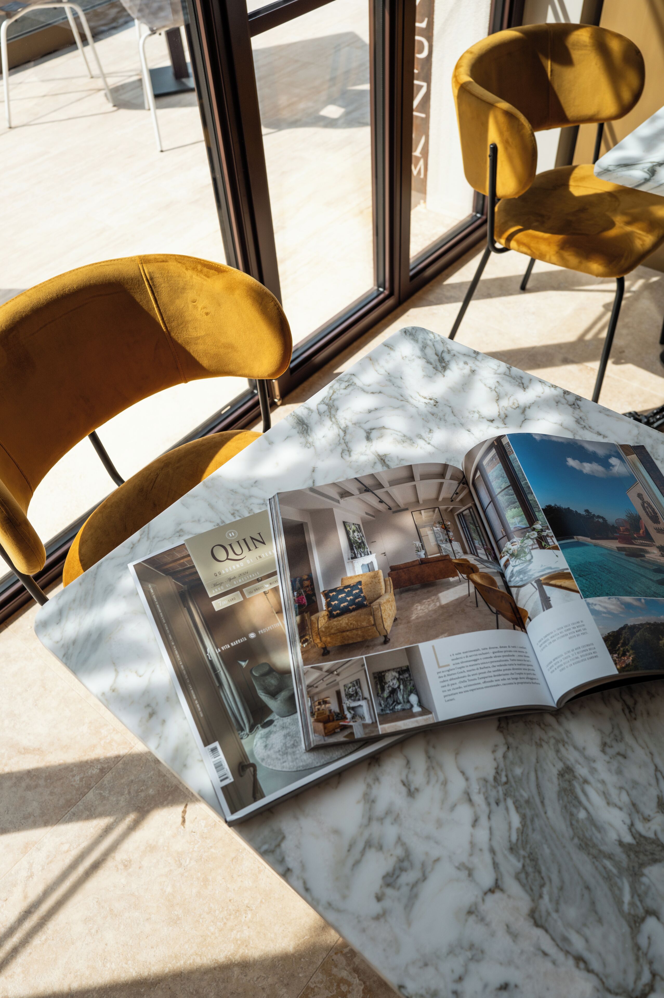 Revista sobre uma mesa de mármore, com vista para um quarto através de uma janela.