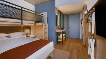 Quarto de hotel moderno com beliche, pequena escrivaninha, toucador com espelho e guarda-roupa de madeira.