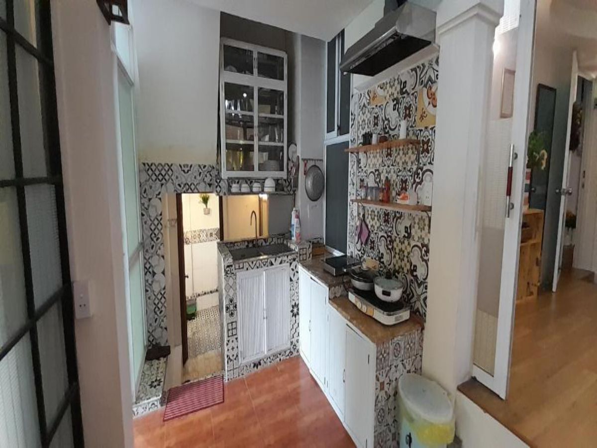 Uma cozinha compacta com armários brancos, painel de fundo estampado e uma pequena janela.