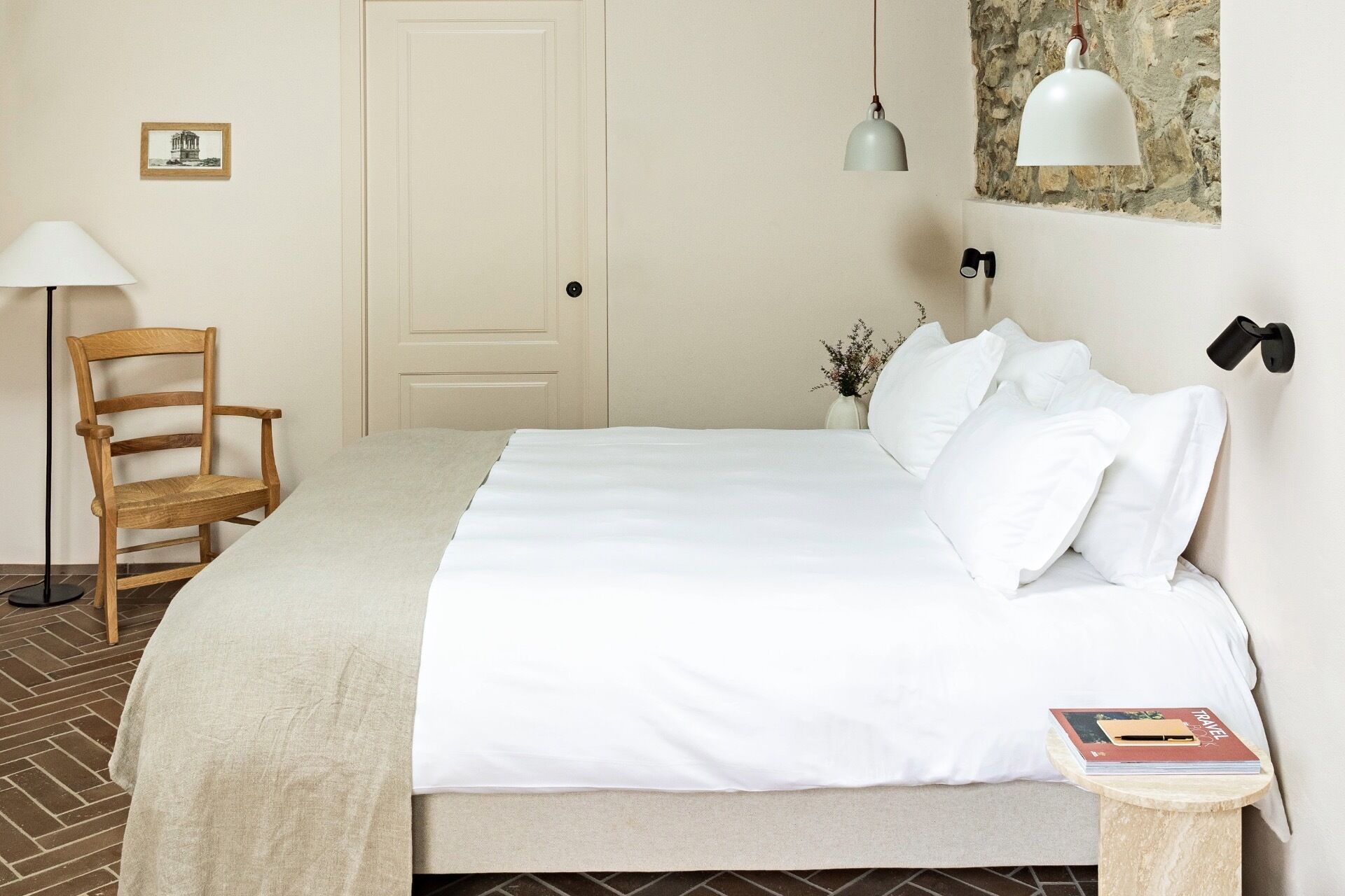 Quarto com cama, cadeira, mesa de cabeceira, luminária e iluminação embutida na parede.