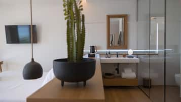 Um banheiro moderno com toucador de madeira, um espelho grande e um vaso com planta.