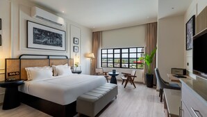 Quarto de hotel com uma cama grande, mesas de cabeceira, uma escrivaninha, uma cadeira, uma televisão e uma janela com vista.