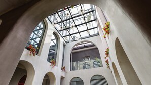 Um interior espaçoso com tetos abobadados e janelas amplas, com luminárias pendentes e decorações florais.