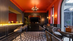 Uma área de bar moderna com um chão de padrão geométrico, paredes pretas e vermelhas e um lustre.