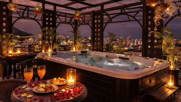 Terraço no topo com hidromassagem, área de refeições e vista para a cidade ao entardecer.