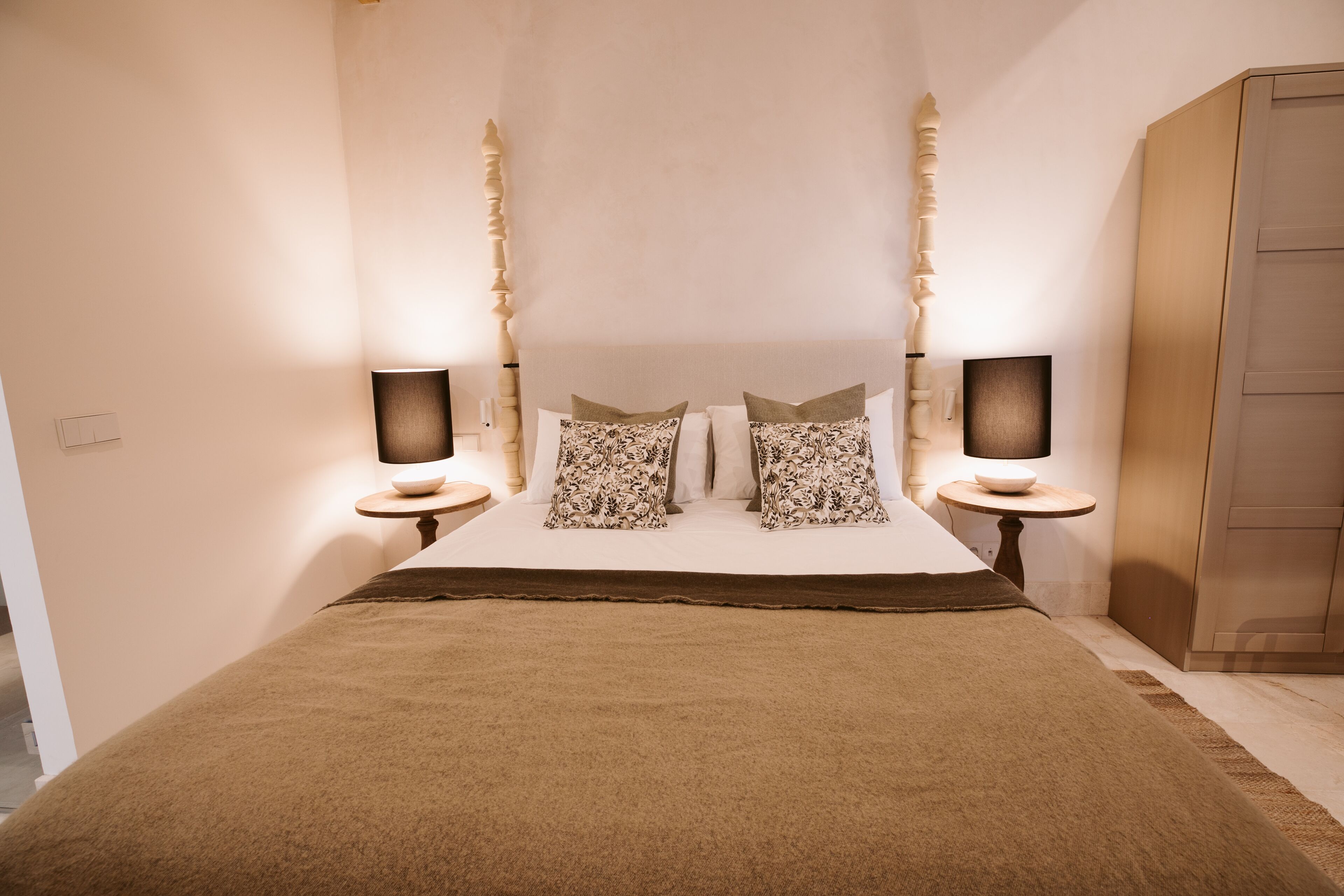 Quarto com uma cama grande, duas mesas de cabeceira, uma cômoda e um abajur em cada mesa.
