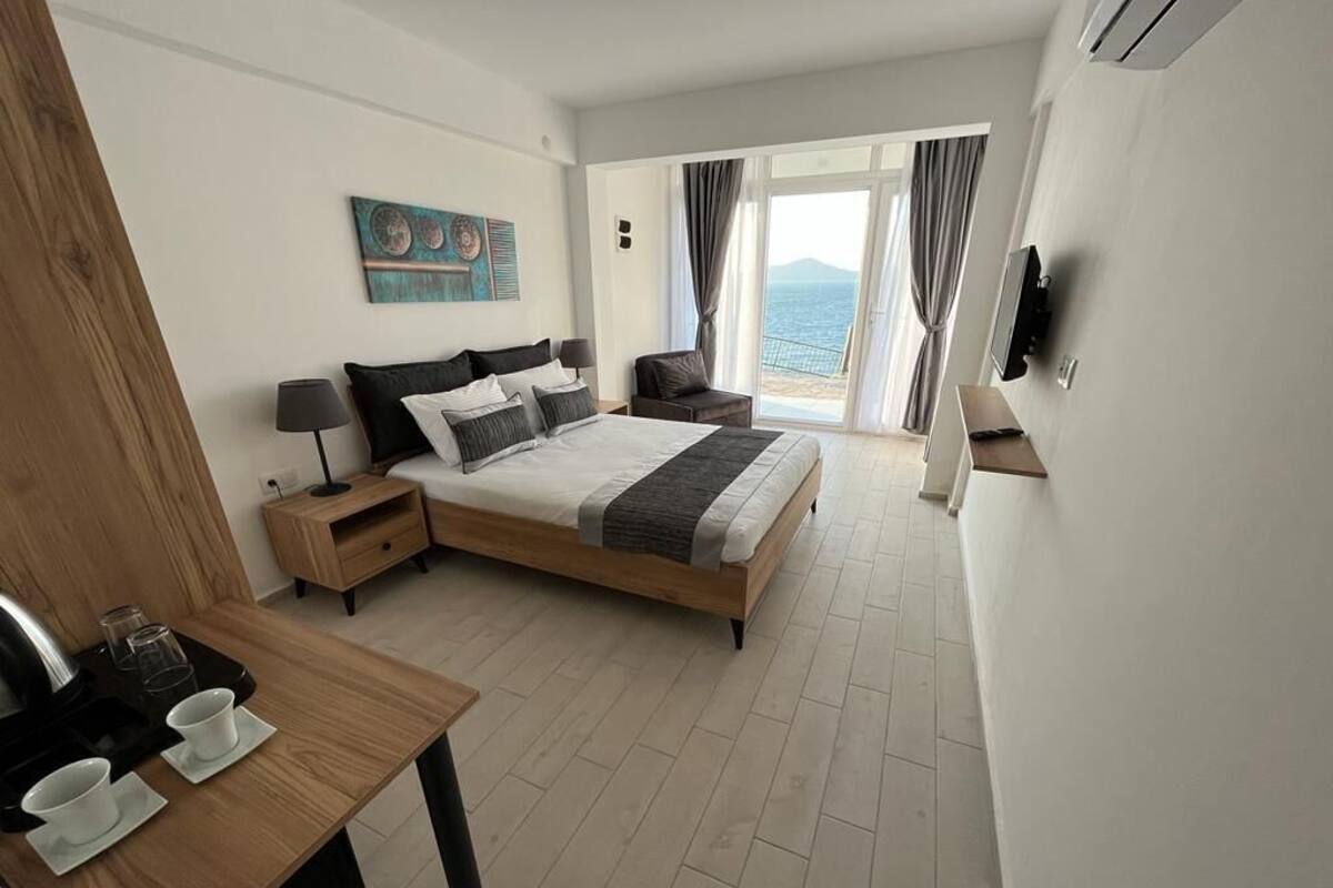 Quarto de hotel com cama, mesa de cabeceira e vista para o mar.