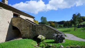 Uma ponte de pedra que leva a um edifício com fachada de pedra e chaminé.