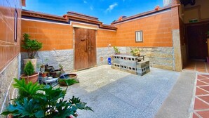 Um pátio com parede de tijolos, porta de madeira e vasos de plantas.