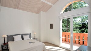 Quarto com cama, mesas de cabeceira, luminária, janela e vista para uma parede de tijolos.