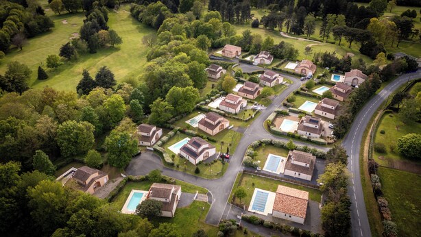 Vista aérea de uma área residencial com casas, ruas e um campo de golfe.