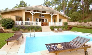 Uma casa de dois andares com varanda coberta e piscina.