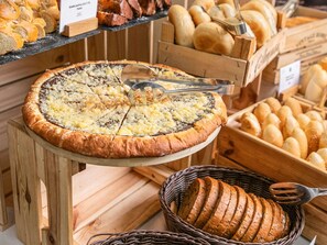 Exposição de pães e uma torta grande em uma padaria.
