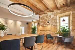Interior moderno com vigas de madeira expostas, parede de pedra e mesa de jantar de madeira com cadeiras.