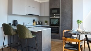 Cozinha moderna com armários cinzas, uma ilha central e banquetas.