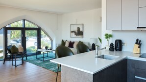 Uma cozinha moderna com uma ilha central, área de refeições com sofá e cadeiras, e uma janela grande com vista para o exterior.